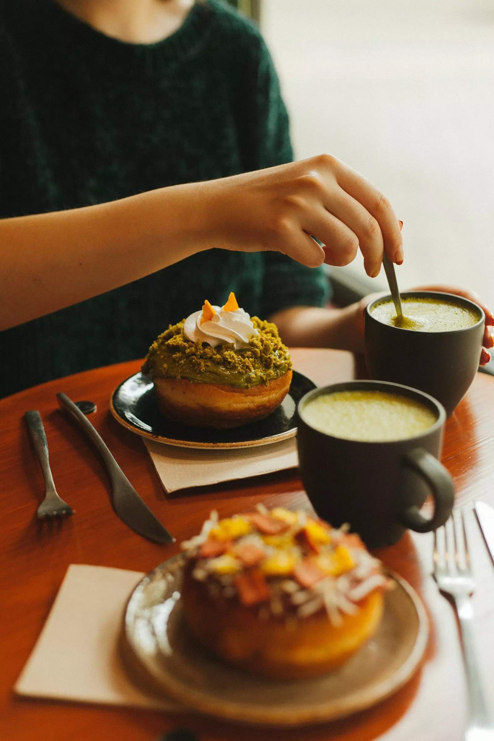 Donat berperisa dan donat manis bersebelahan dengan dua cawan matcha latte di Bite Me Café