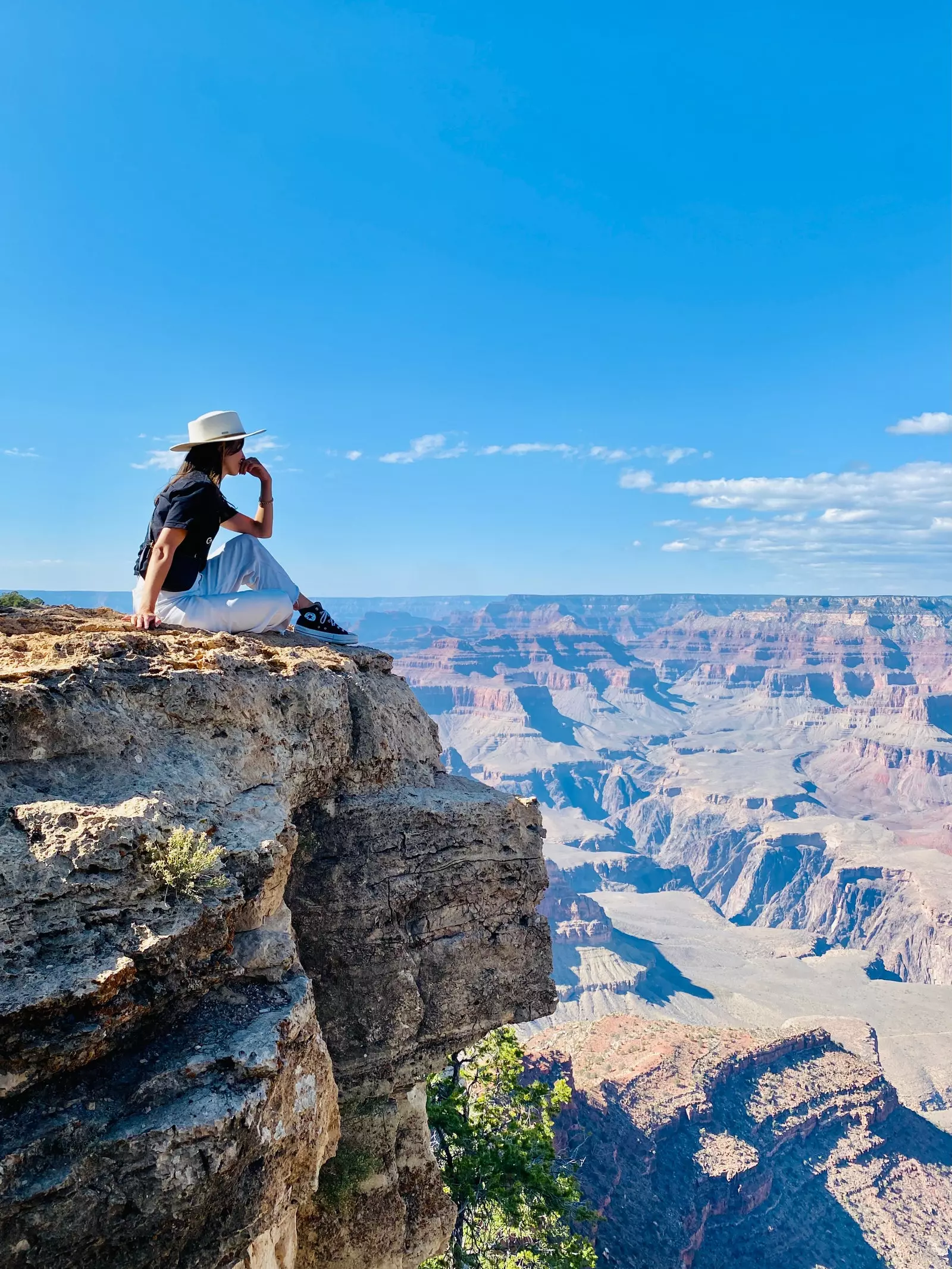 La scrittrice Esme Benjamin seduta sul bordo del Grand Canyon sotto un cielo blu